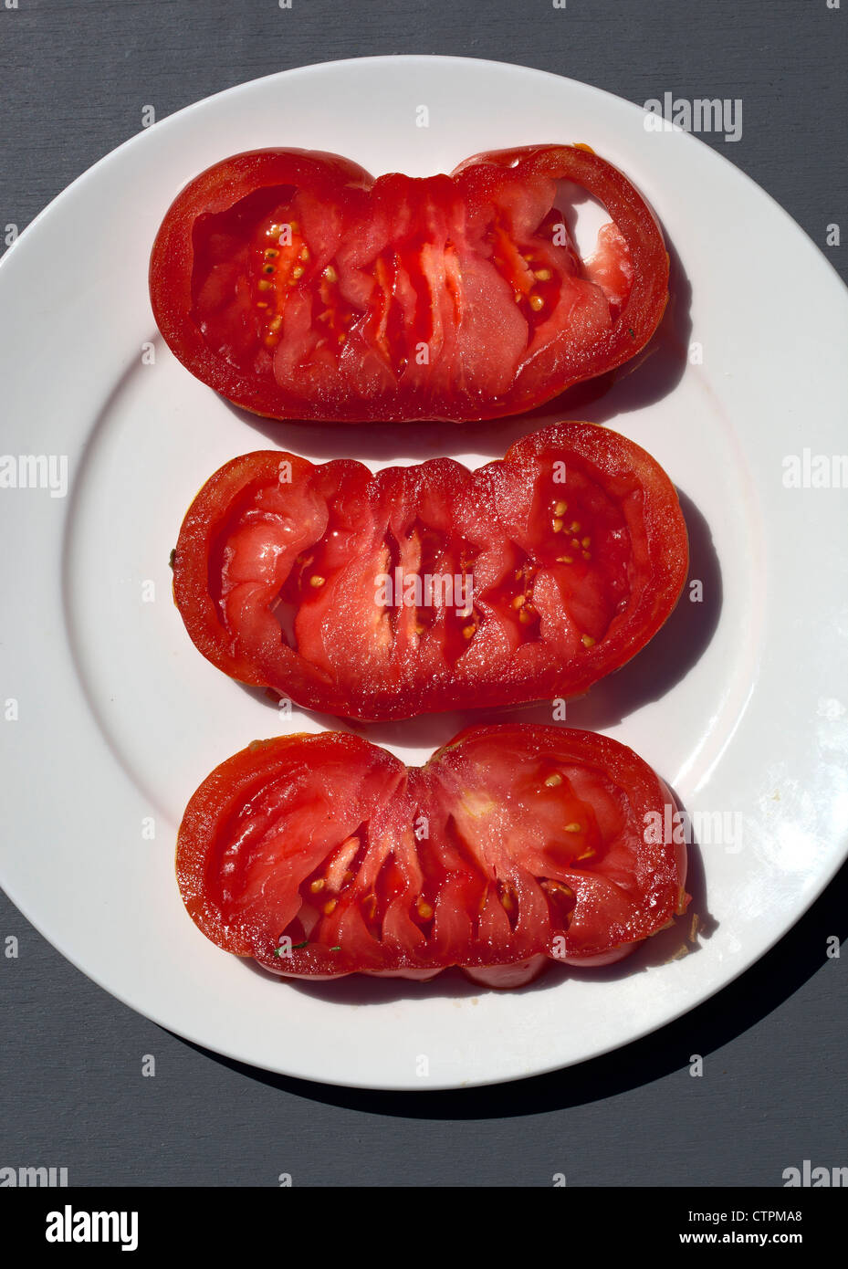 Slices of Giant Pink Beef Tomato (Zapotec Pleated) on plate Stock Photo ...