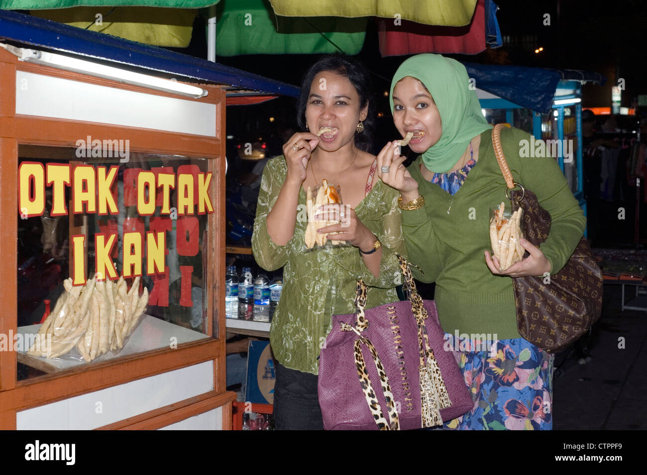 two local sisters eating a local fish snack at the night market batavia ...