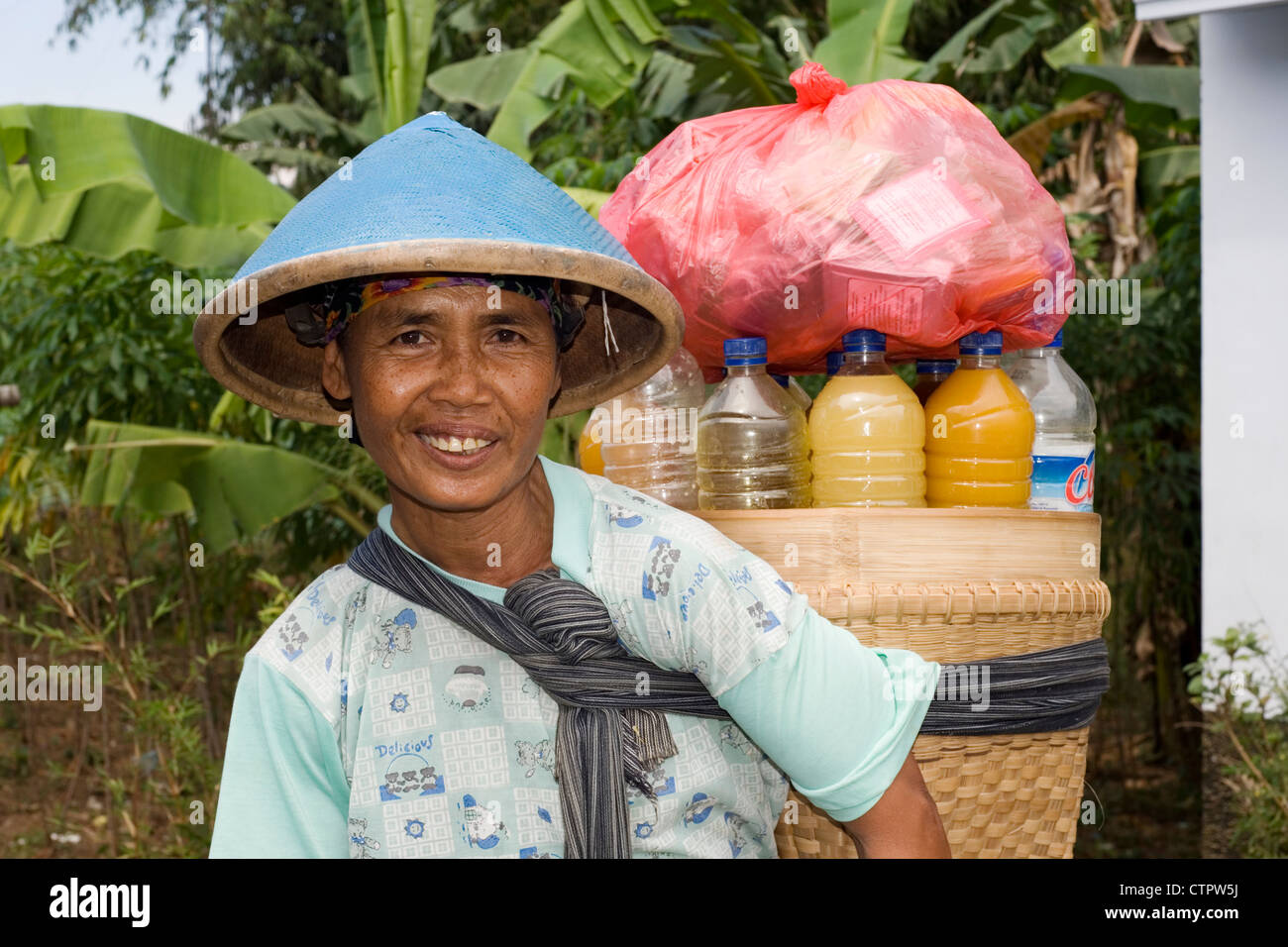 local female villager in rural village street with basket of ...