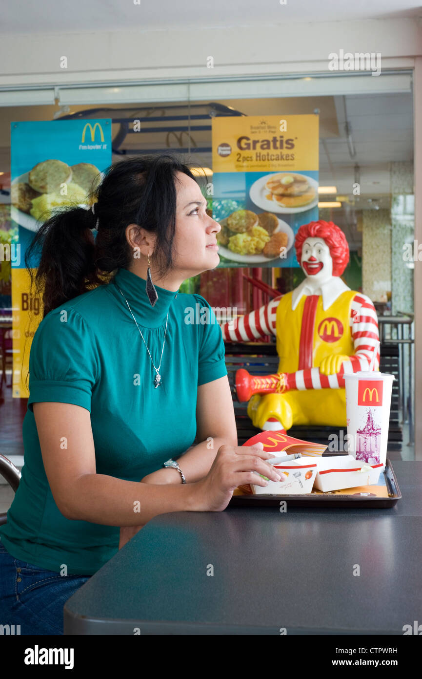 local woman relaxes with a cigarette after eating a meal at her table ...