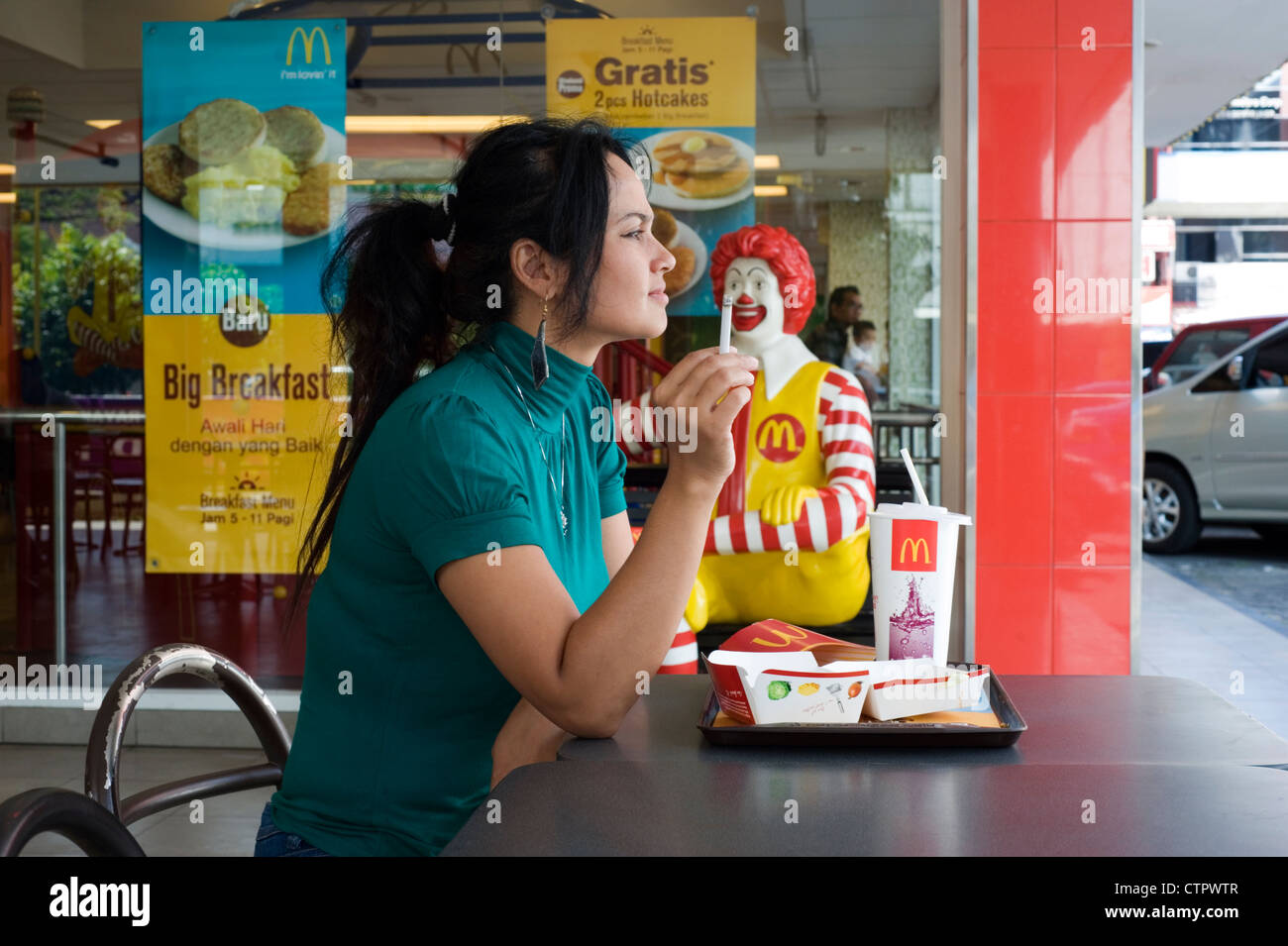 local woman relaxes with a cigarette after eating a meal at her table ...