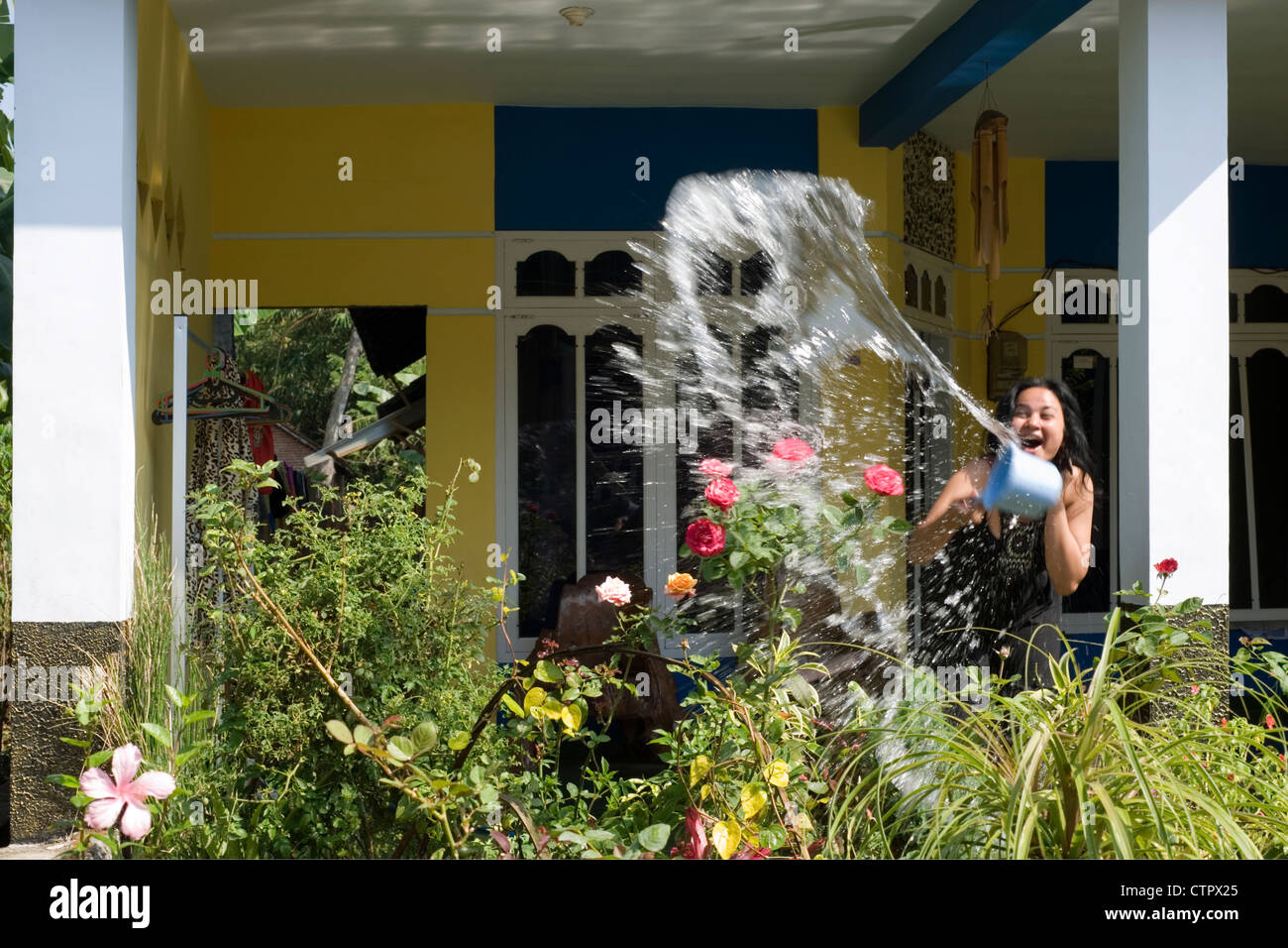 young local woman throwing water over her garden flowers Stock Photo ...