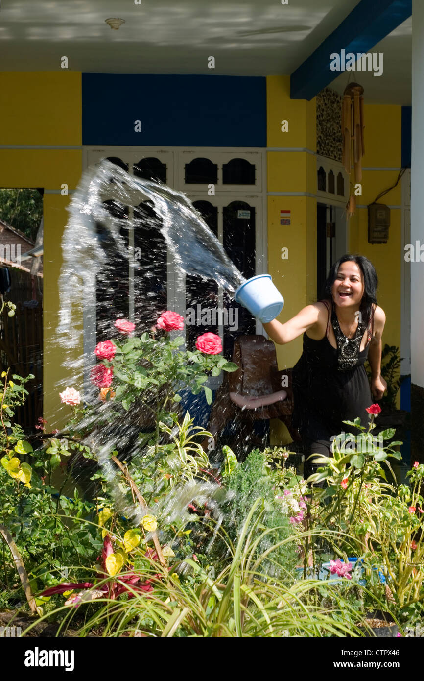 young local woman throwing water over her garden flowers Stock Photo ...