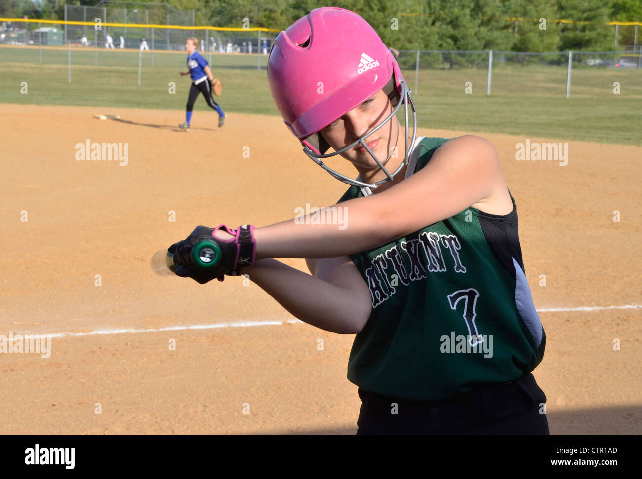 A female softball batter takes some warmup swings before she comes up ...