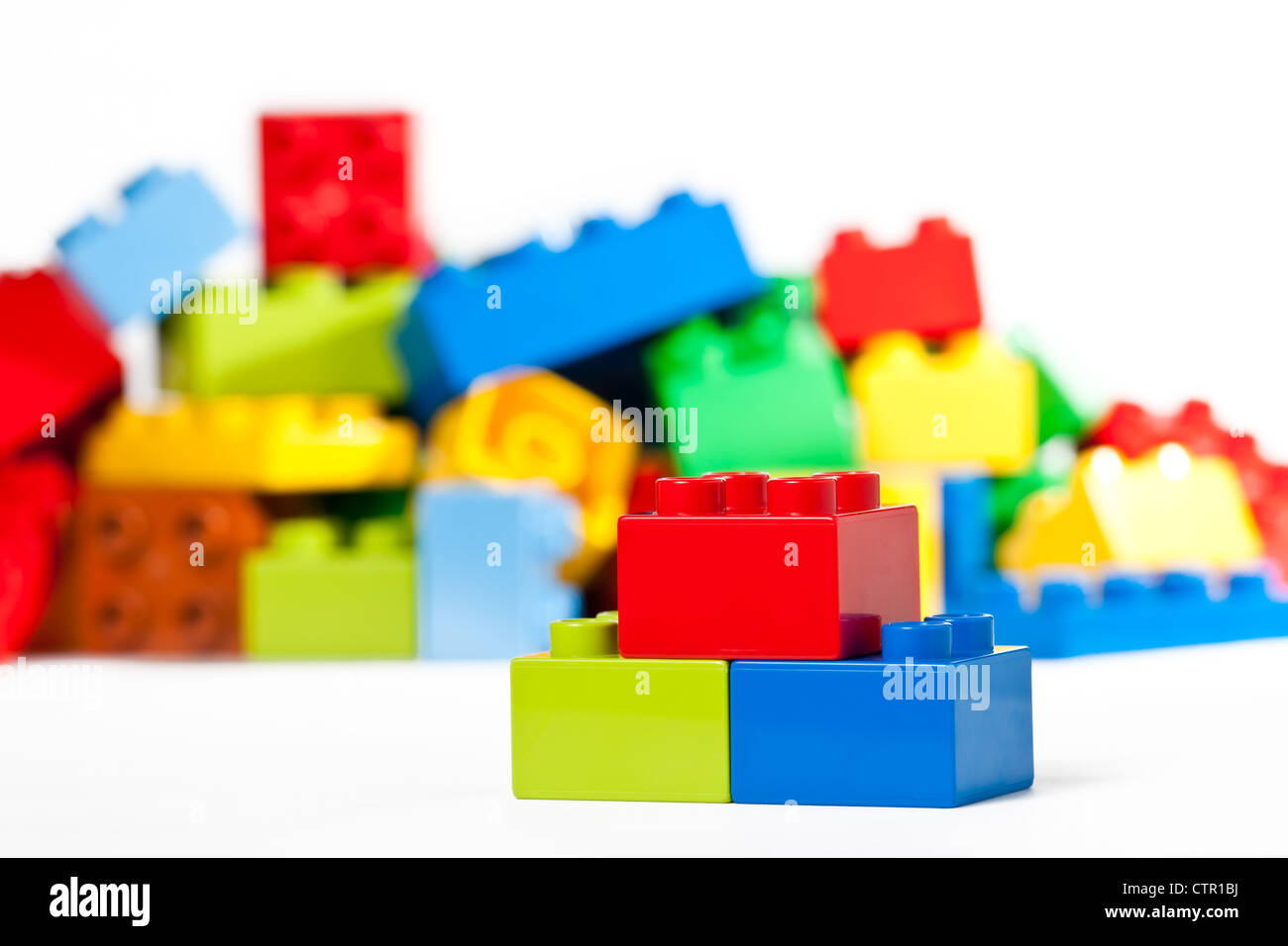 Three parts of brick toys with heaps of toy parts blurred at the ...