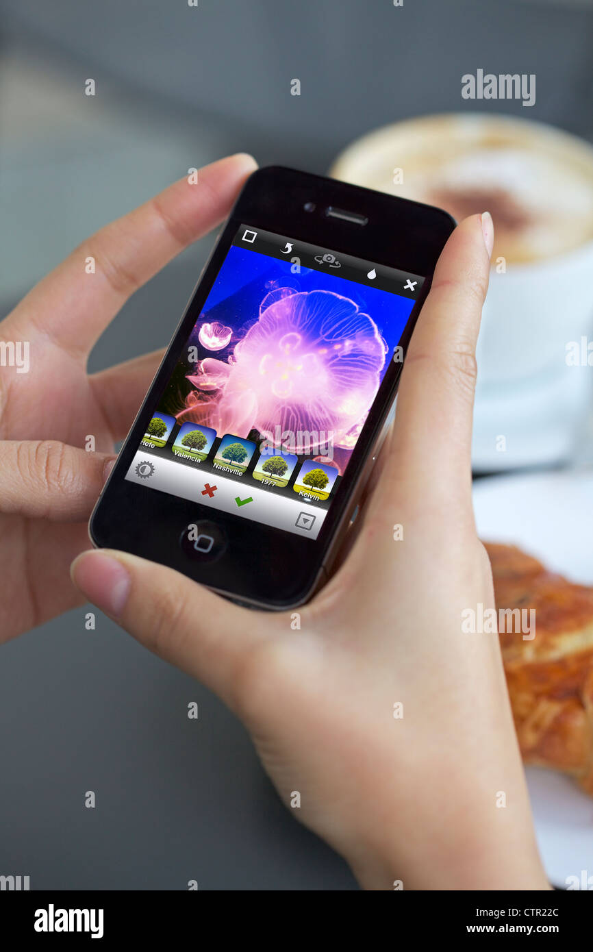 Close up picture of woman handholding an iphone using Instagram camera ...