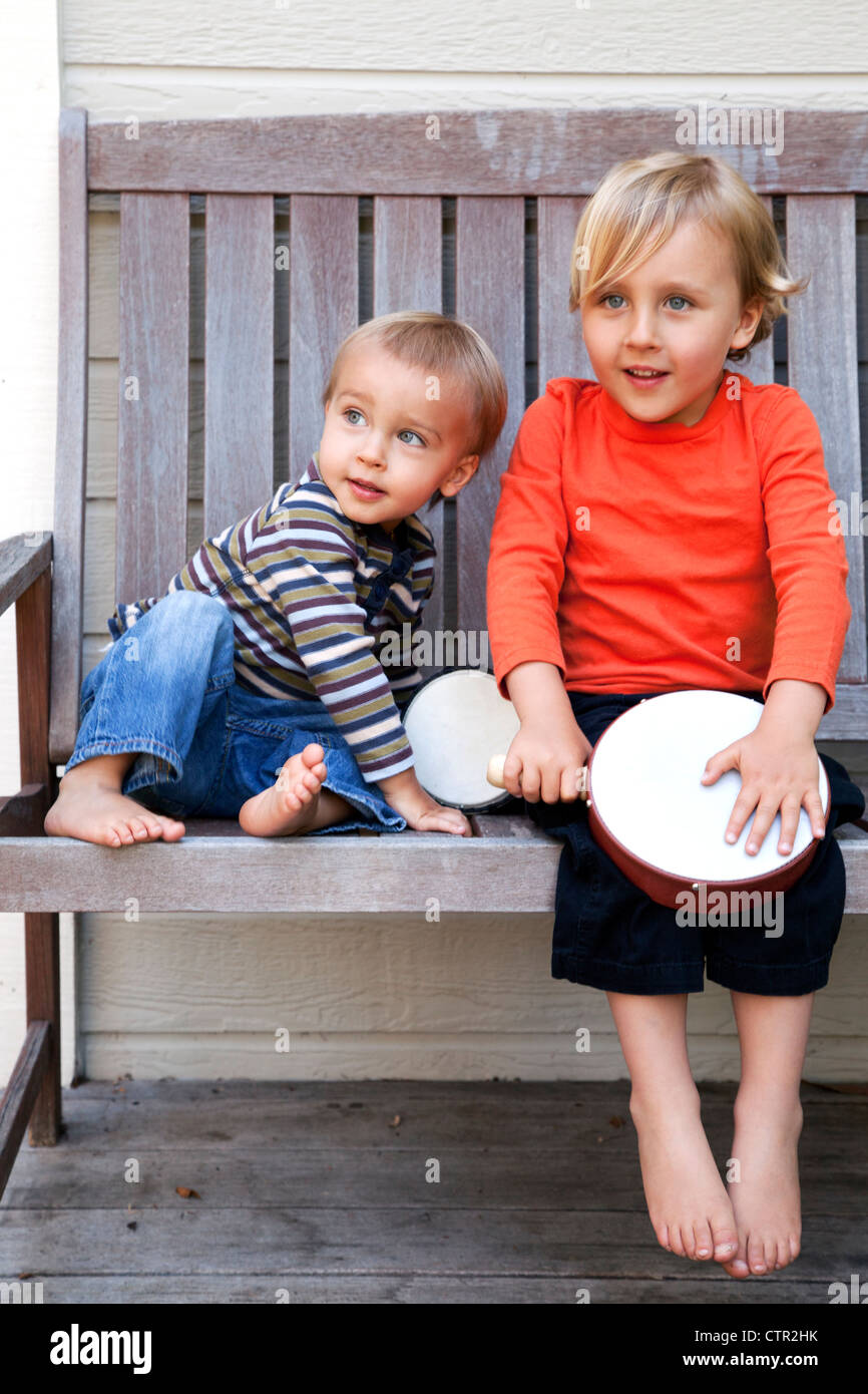 Two brothers are sitting on a wooden bench together Stock Photo - Alamy