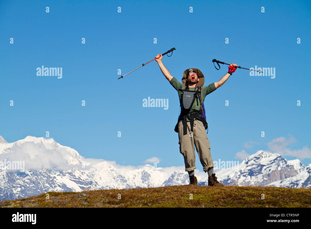 Man rejoicing arms outstretched while hiking tundra ridge between Ruth ...