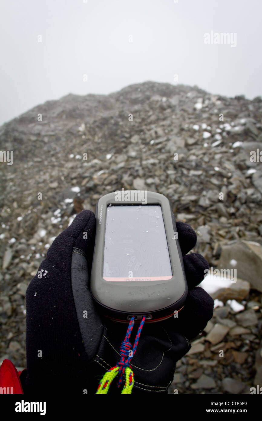 View hand holding GPS navigating fog whiteout on rocky ridge between ...