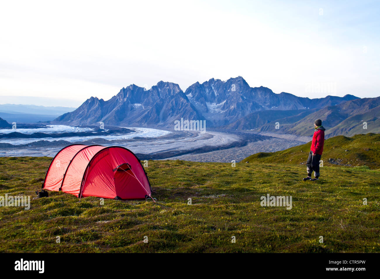 Male backpacker at camp above Ruth Glacier Tokosha Mountains beyond ...