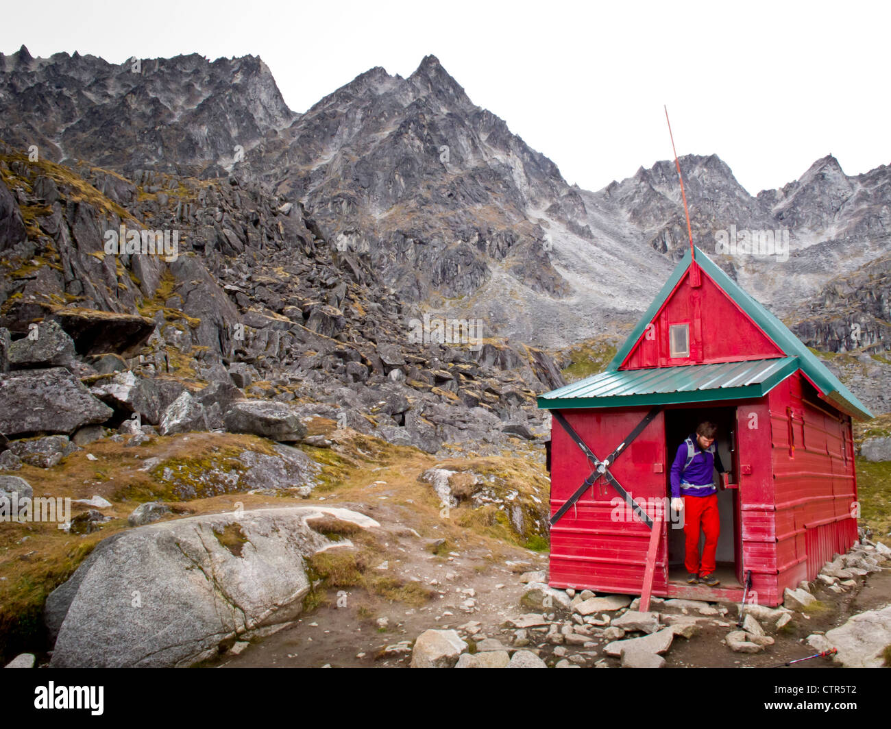 Man standing in the doorway of Mint Hut, Talkeetna Mountains near ...