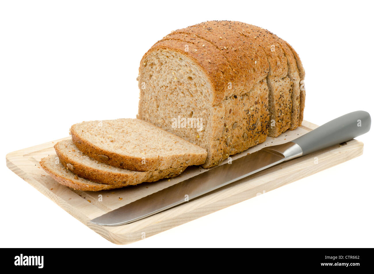 Sliced granary bread loaf on a wooden chopping board with a bread knife ...