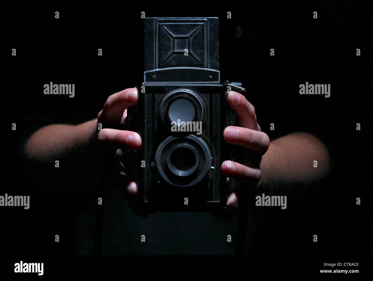 Vintage twin reflex camera held by two hands on black Stock Photo - Alamy