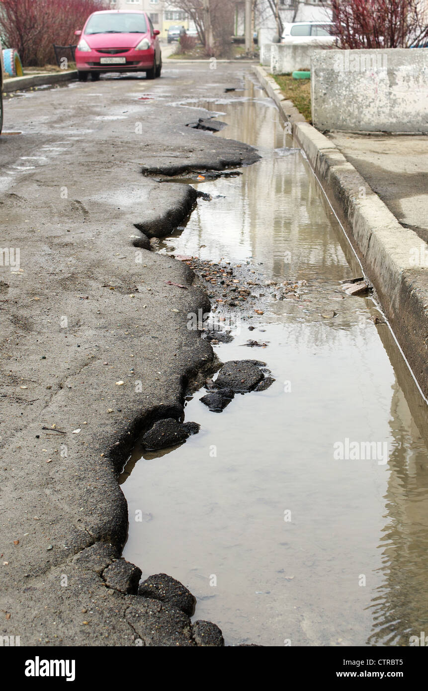 Puddle on damaged road Stock Photo - Alamy