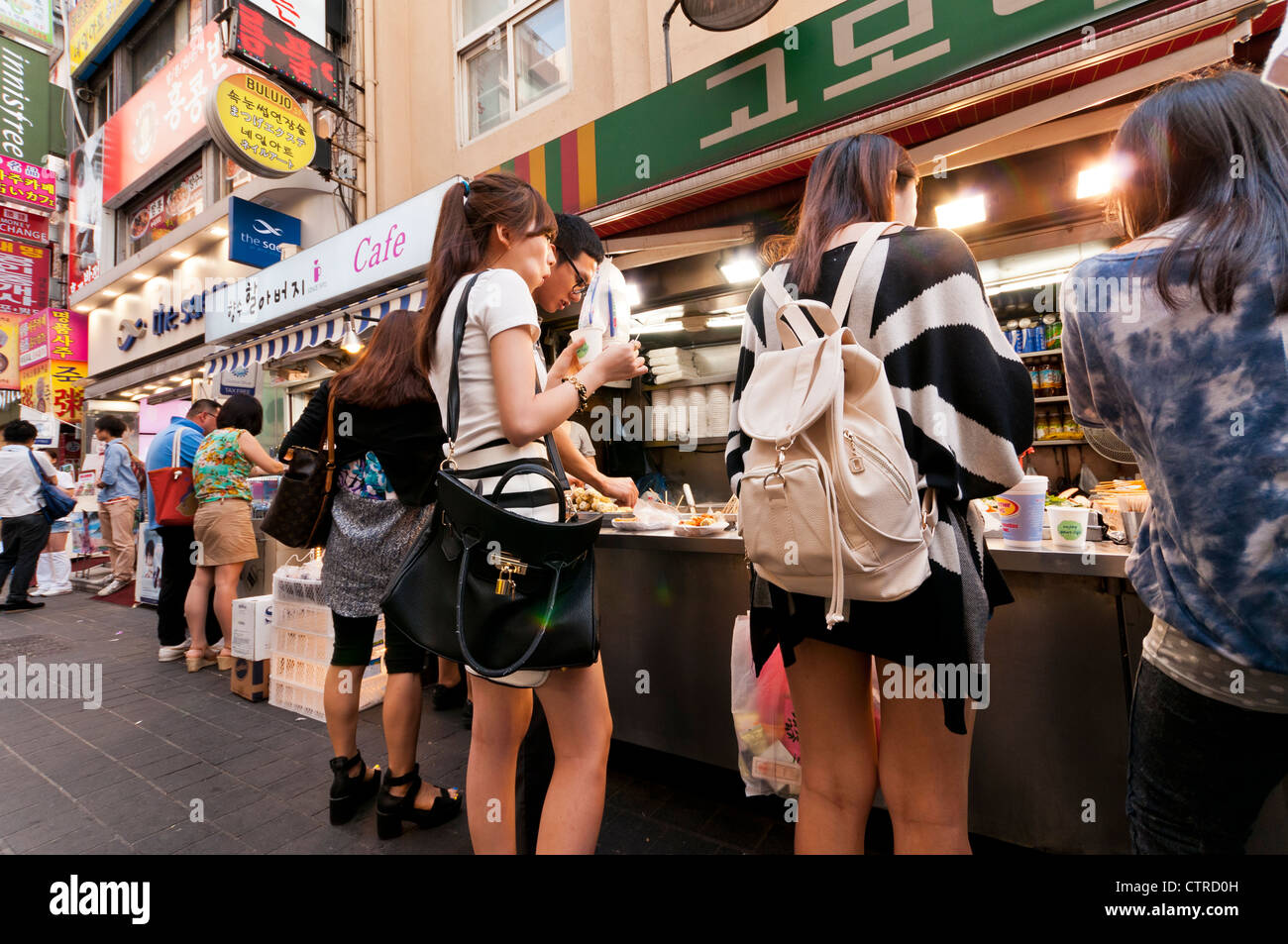 Young women eating at food stall in Myeongdong, Seoul, Korea Stock ...