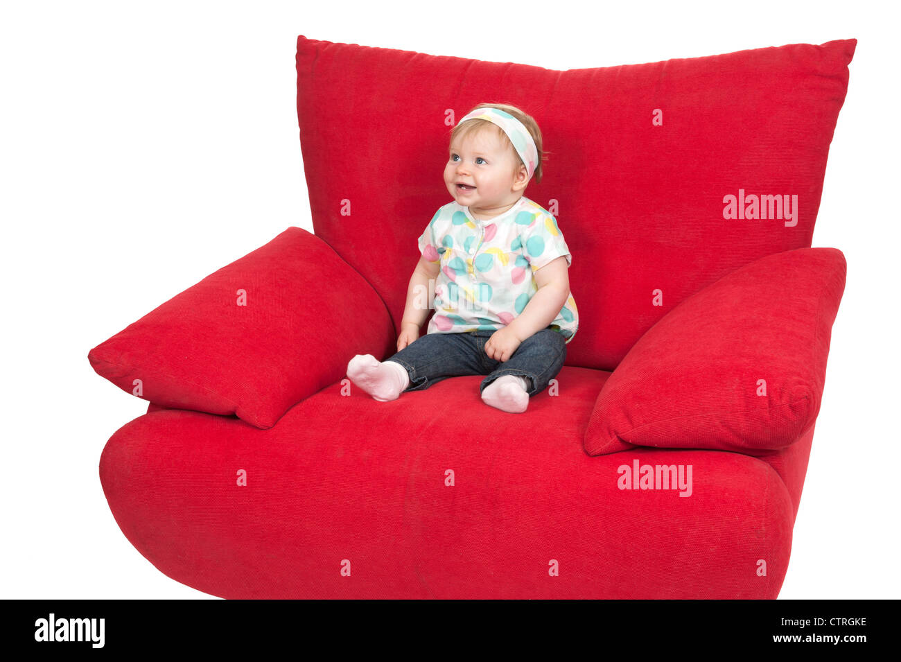 baby girl seated in a big red sofa. Isolated on white background Stock ...
