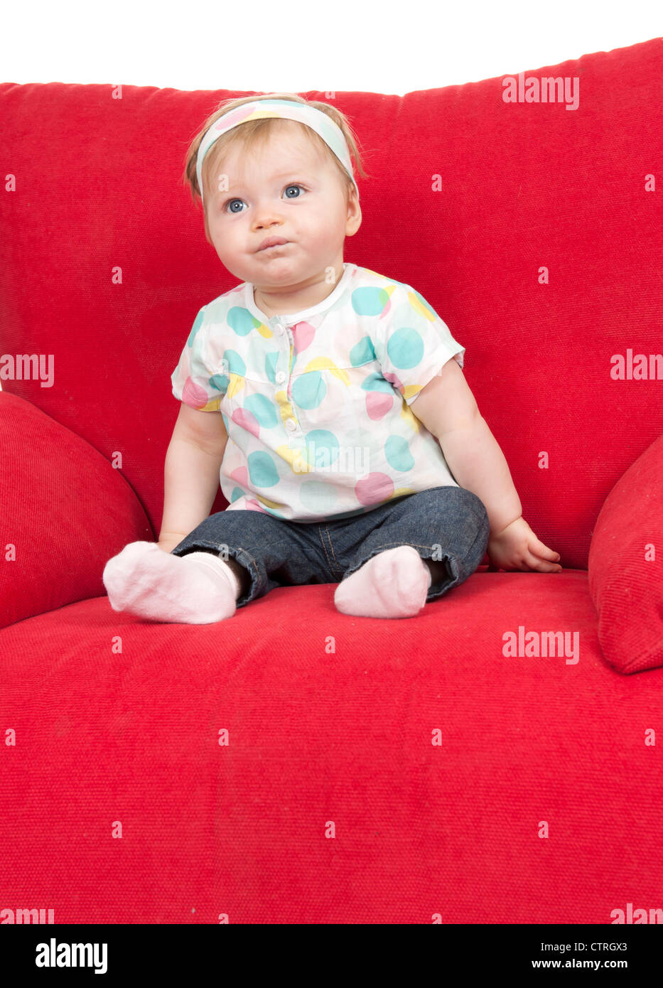 baby girl seated in a big red sofa. Isolated on white background Stock ...