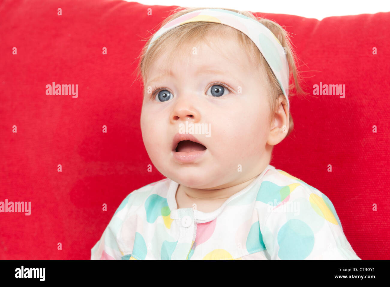 baby girl seated in a red sofa. Isolated on white background Stock ...