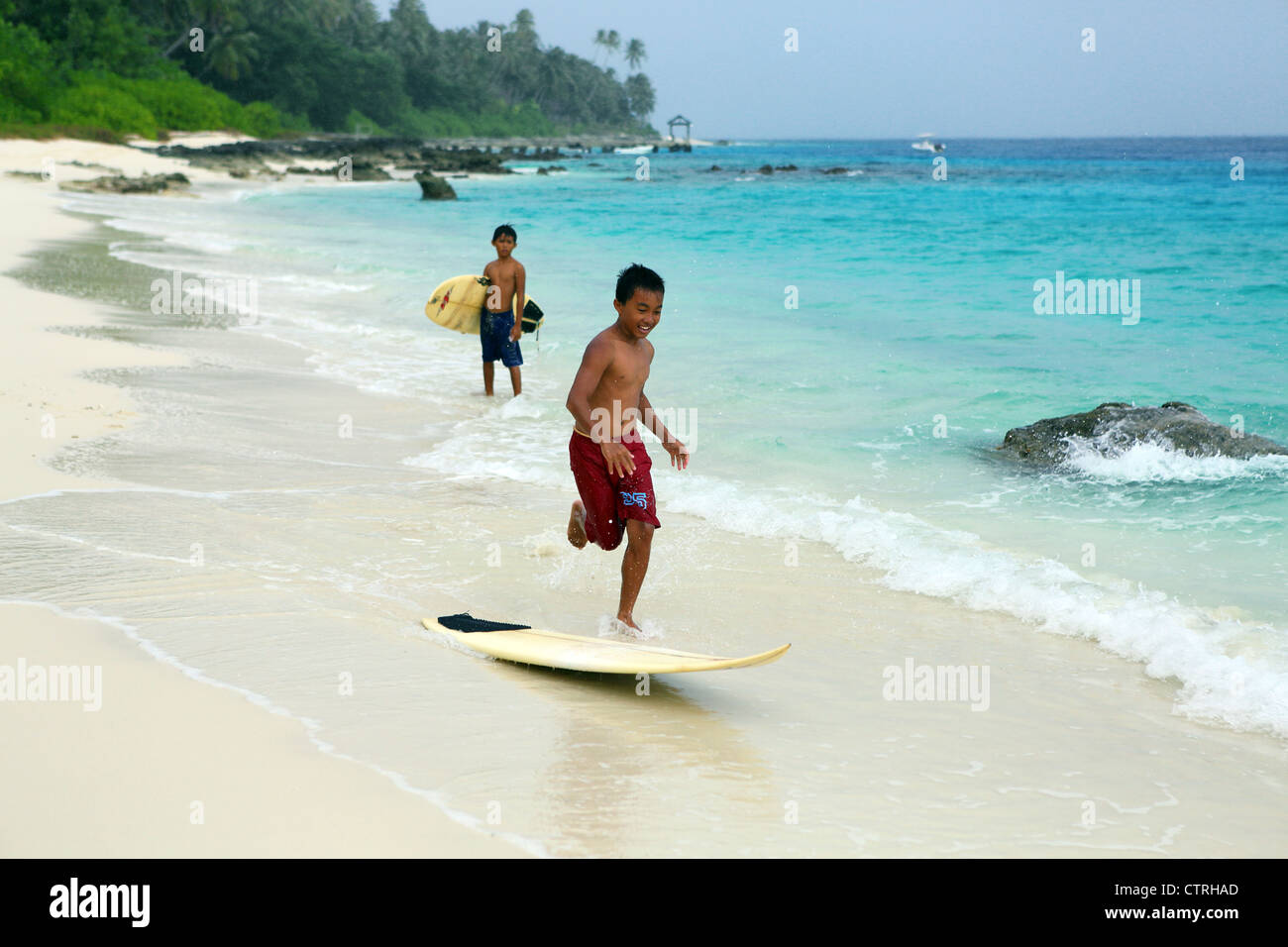 Young Indonesian boys skim-board surfing on the beach at Asu Island in ...