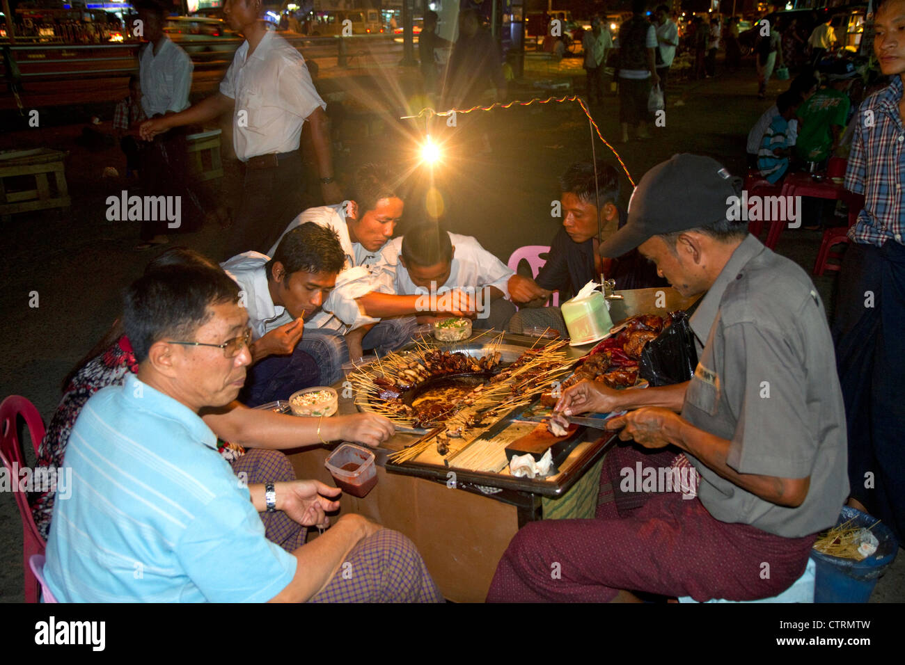 Burmese people eat and drink outdoors near the Sule Paya located in the ...
