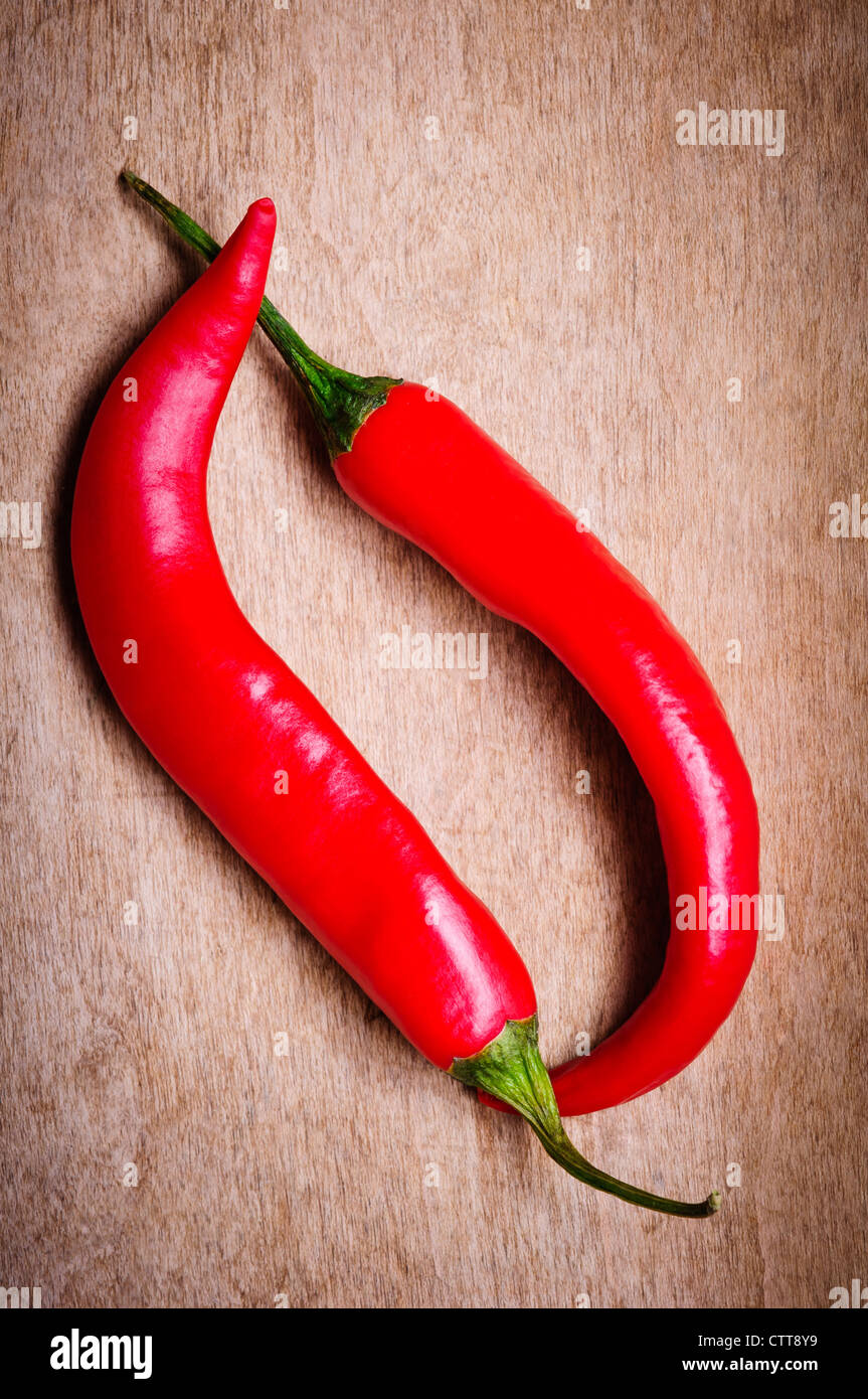 Two hot red pepperoni on a wooden background Stock Photo - Alamy