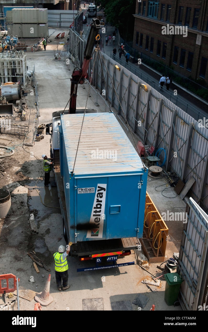 Storage container being lifted onto a back of a truck during ...