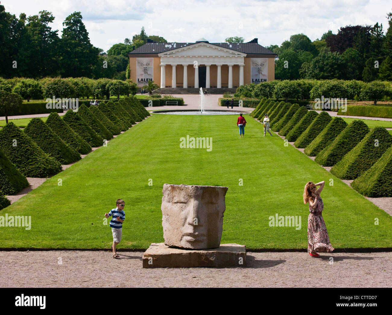 A woman poses for a photograph as a young boy plays around a statue in ...