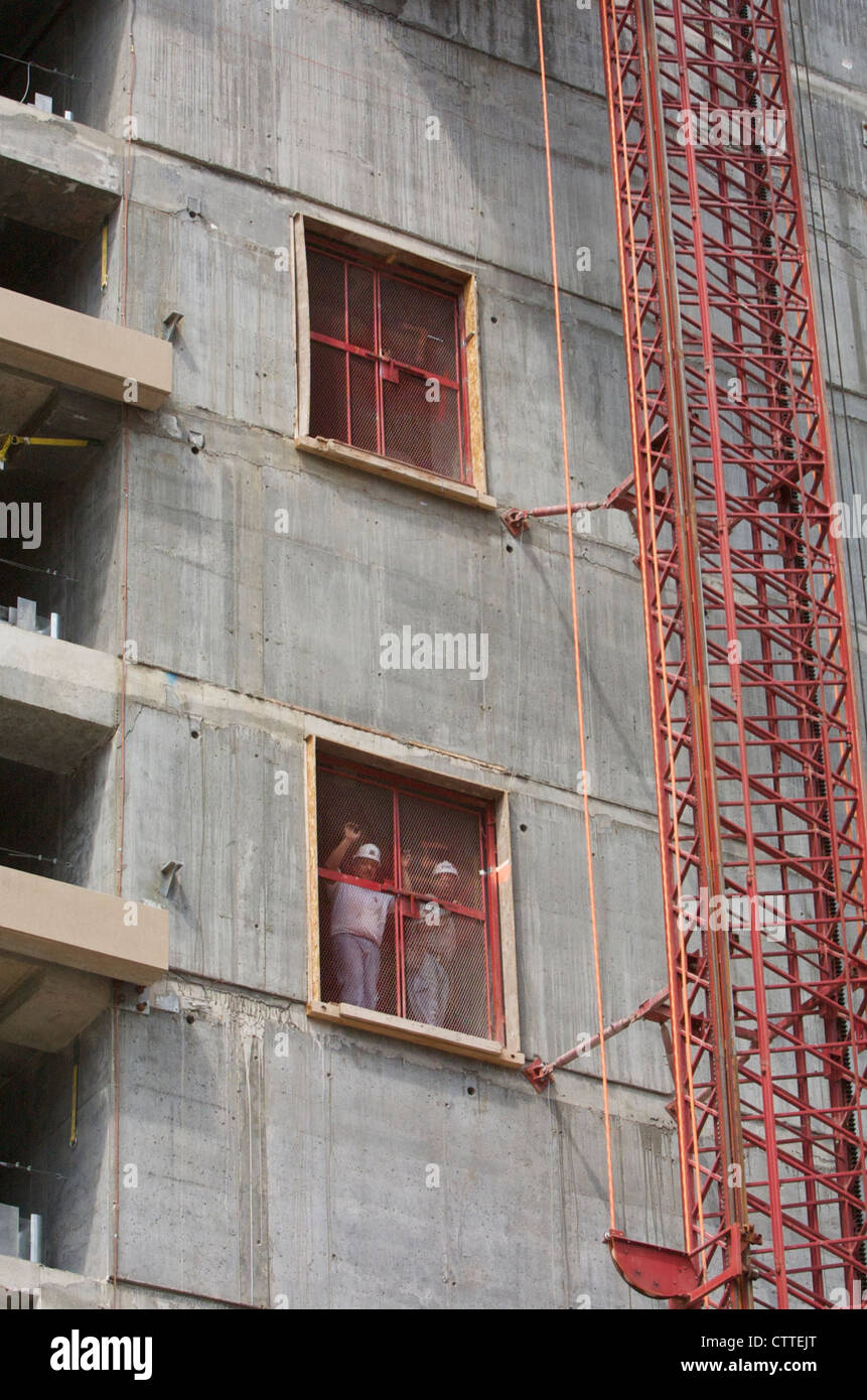 Construction crew members look out the window of a skyscraper under ...