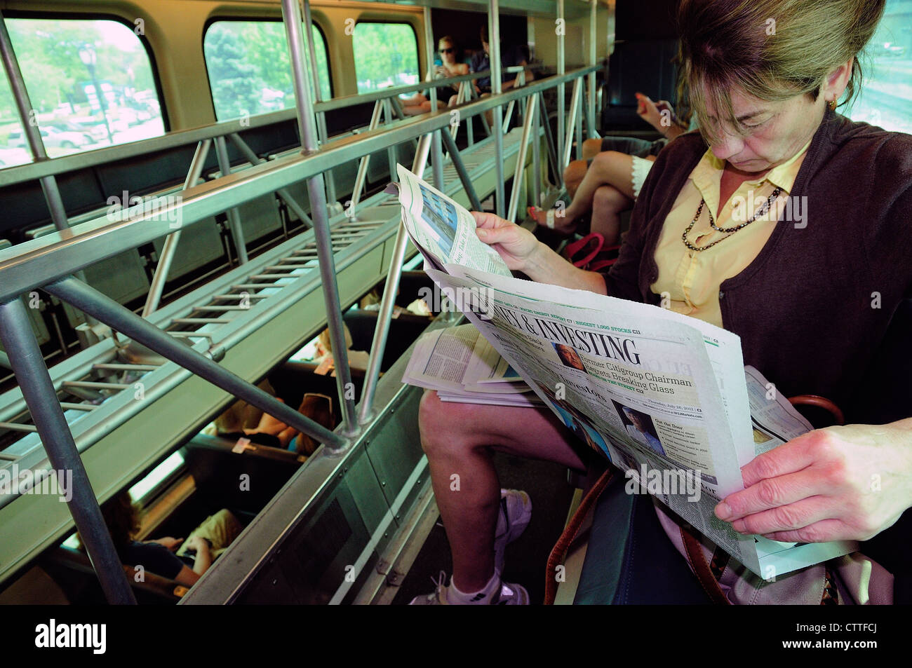 Middle aged woman reading newspaper on commuter train Stock Photo - Alamy