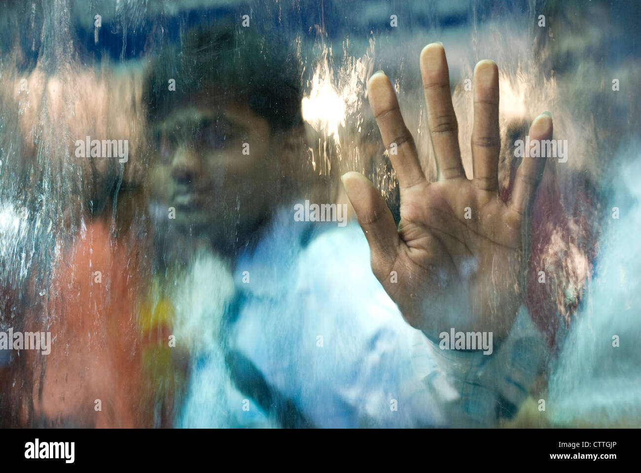 Young man holding his hand against a see through mirror Stock Photo - Alamy