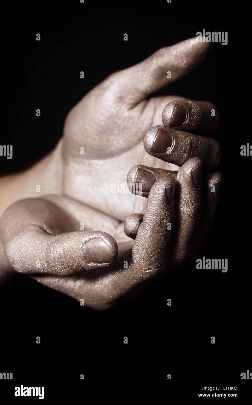 Human bronze hands folded handful on a black background Stock Photo - Alamy