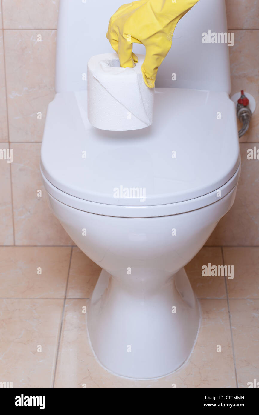 WC hygiene concept, hand in yellow glove holding toilet paper Stock ...