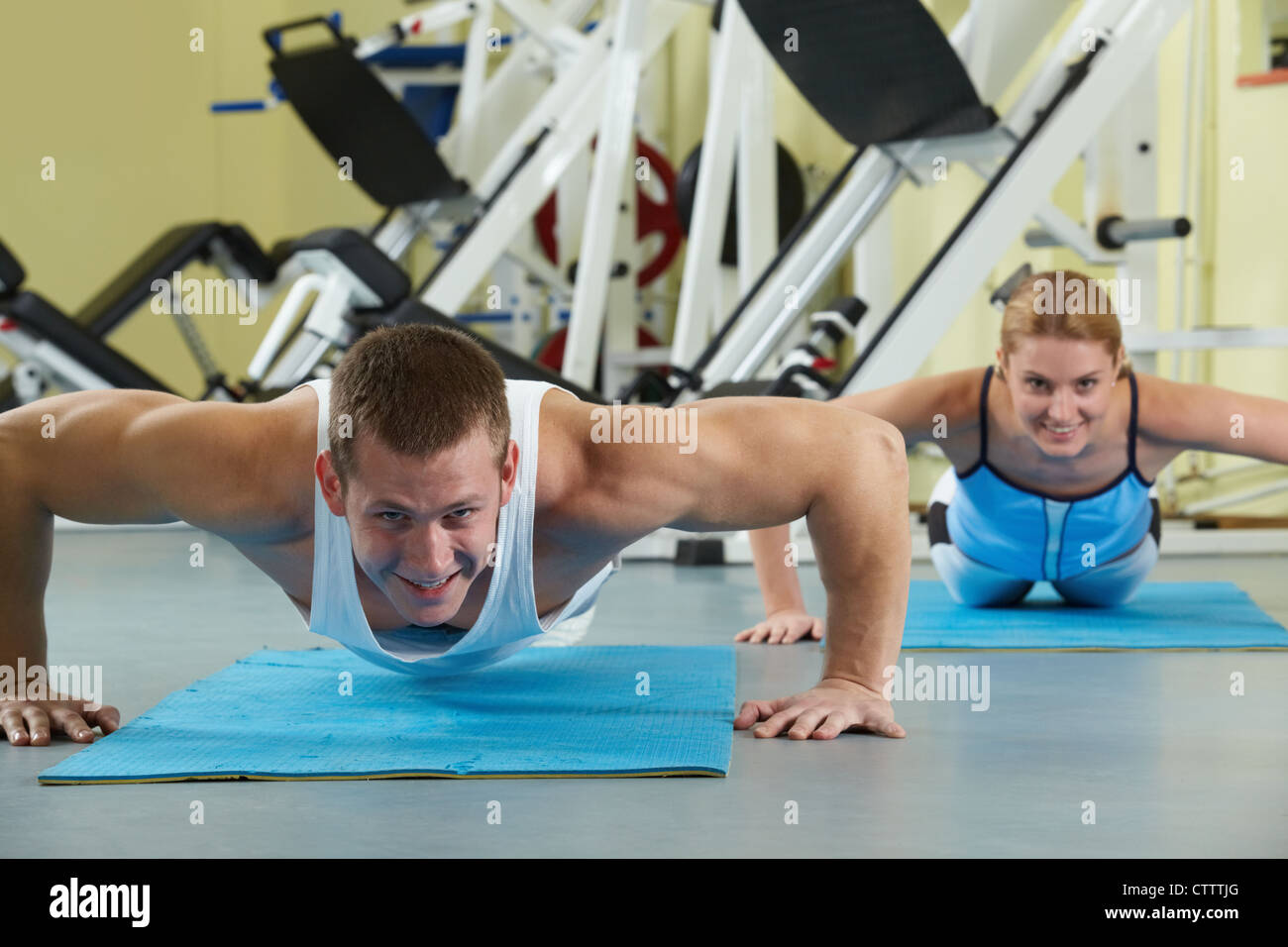 Portrait of sporty couple doing physical exercise and smiling at camera ...