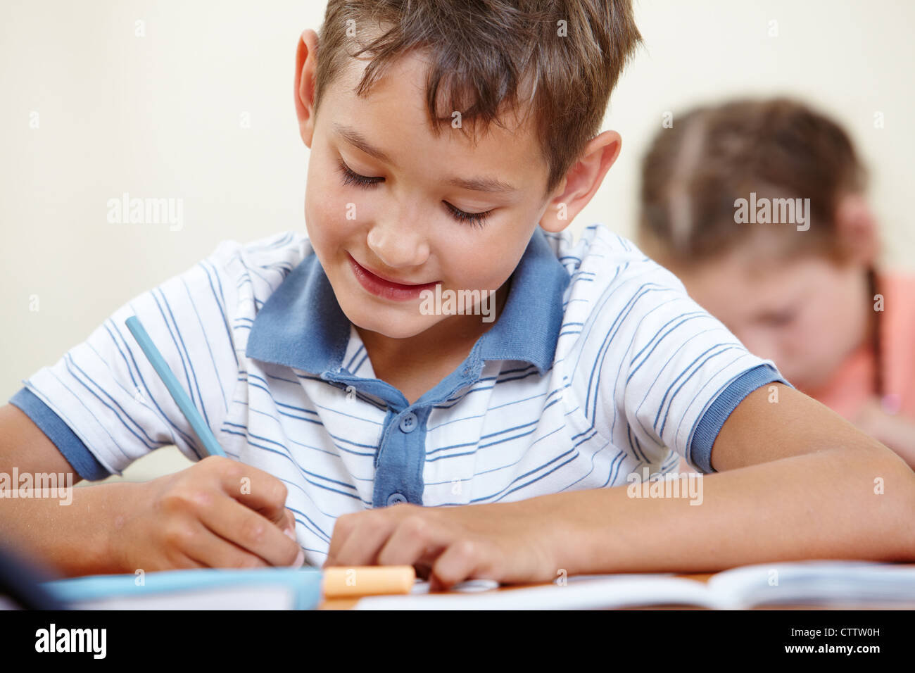 Portrait of smart lad drawing at lesson with classmate on background ...