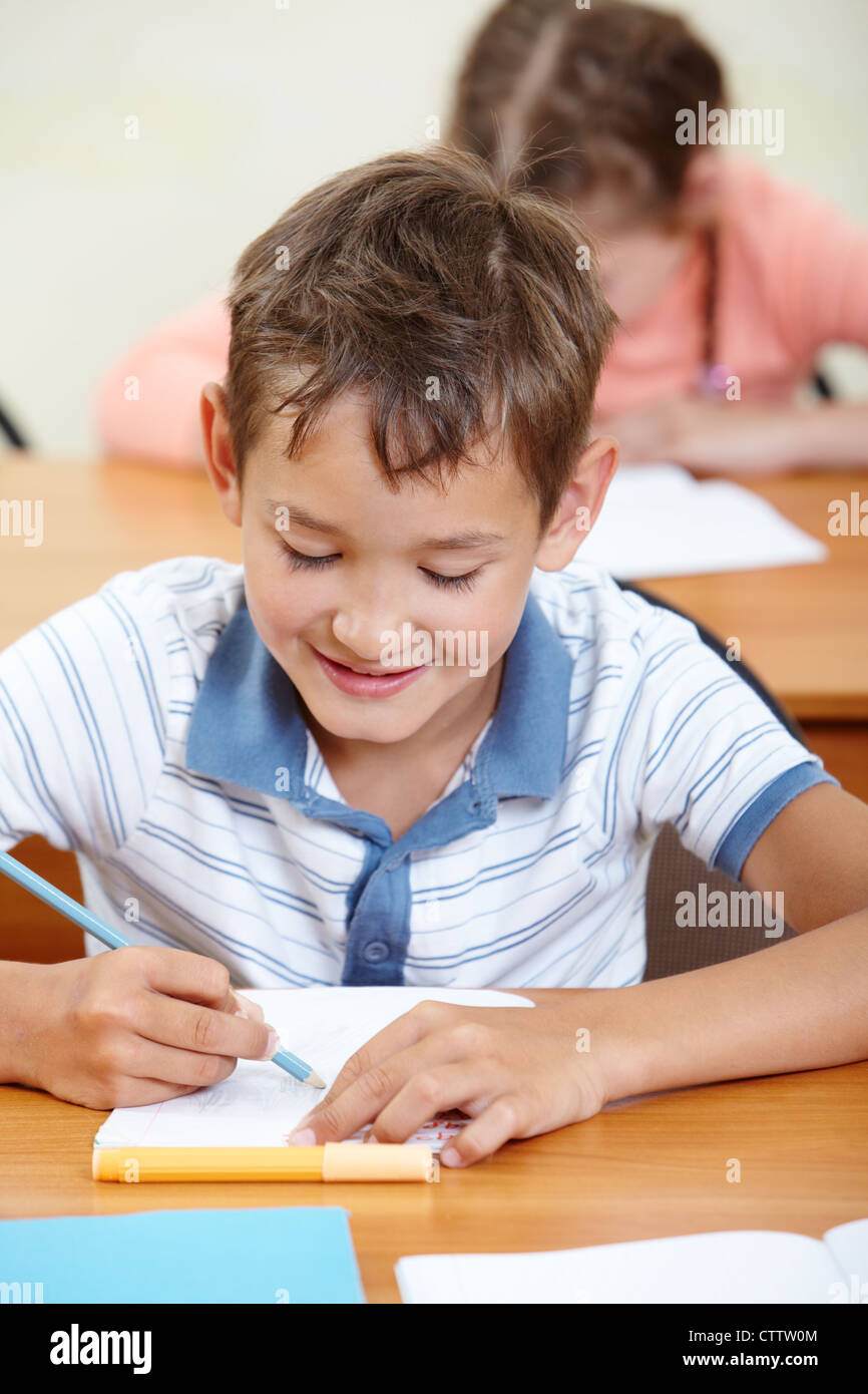 Portrait of smart lad drawing at lesson with classmate on background ...