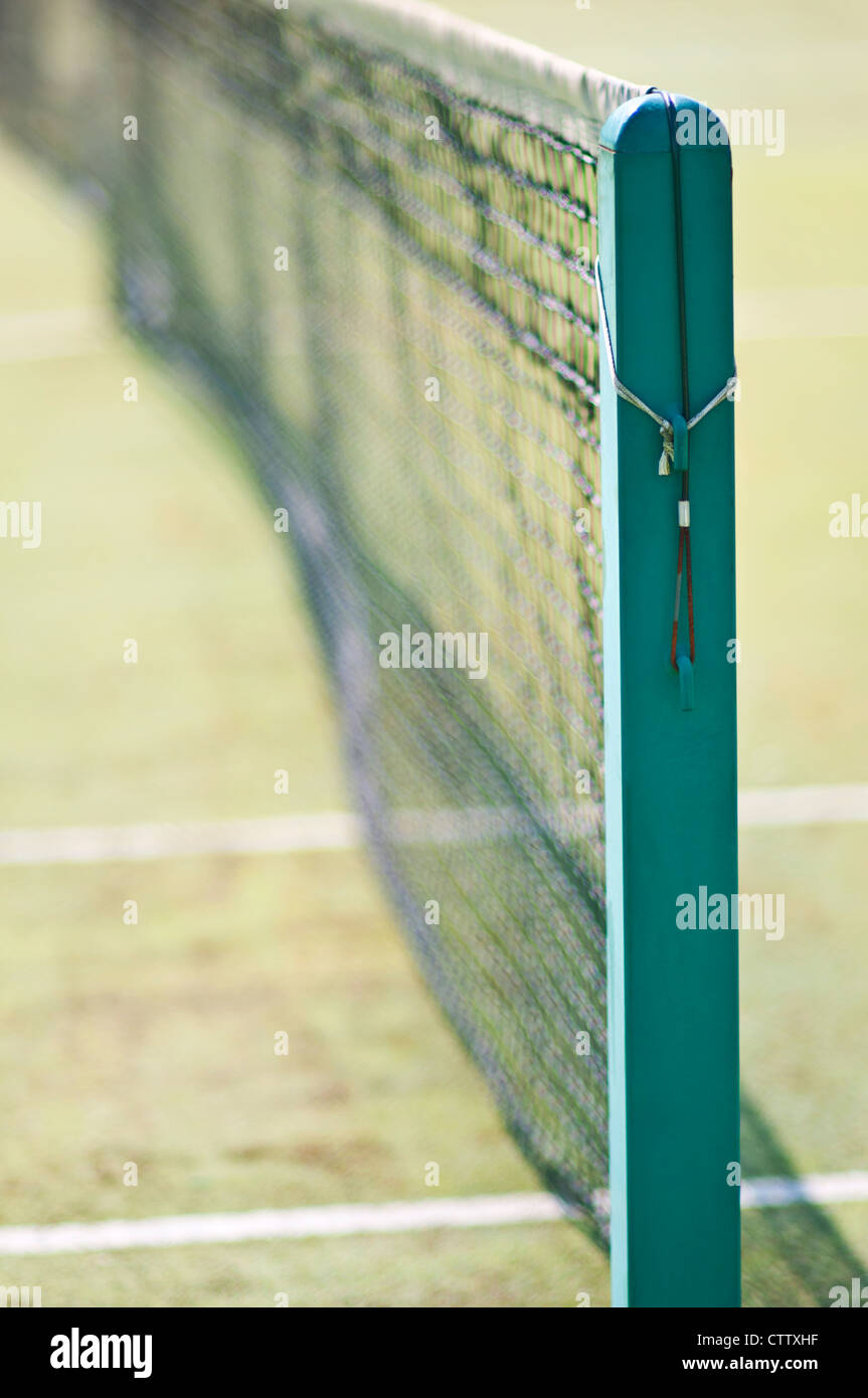 Tennis court net blowing in breeze, casting shadow over sun bleached ...