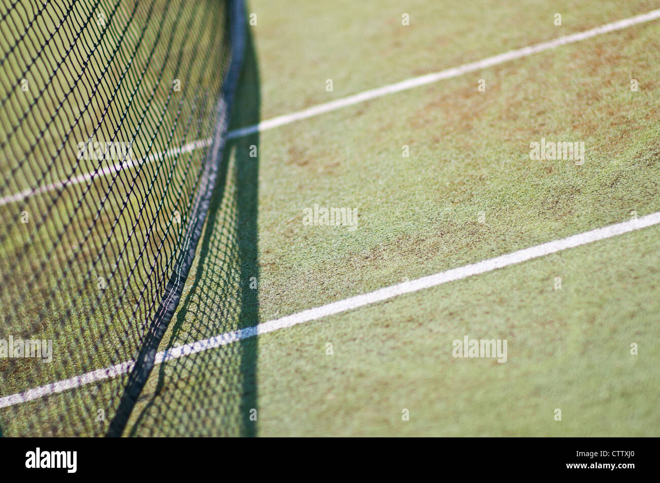 Tennis court net blowing in breeze, casting shadow over sun bleached ...