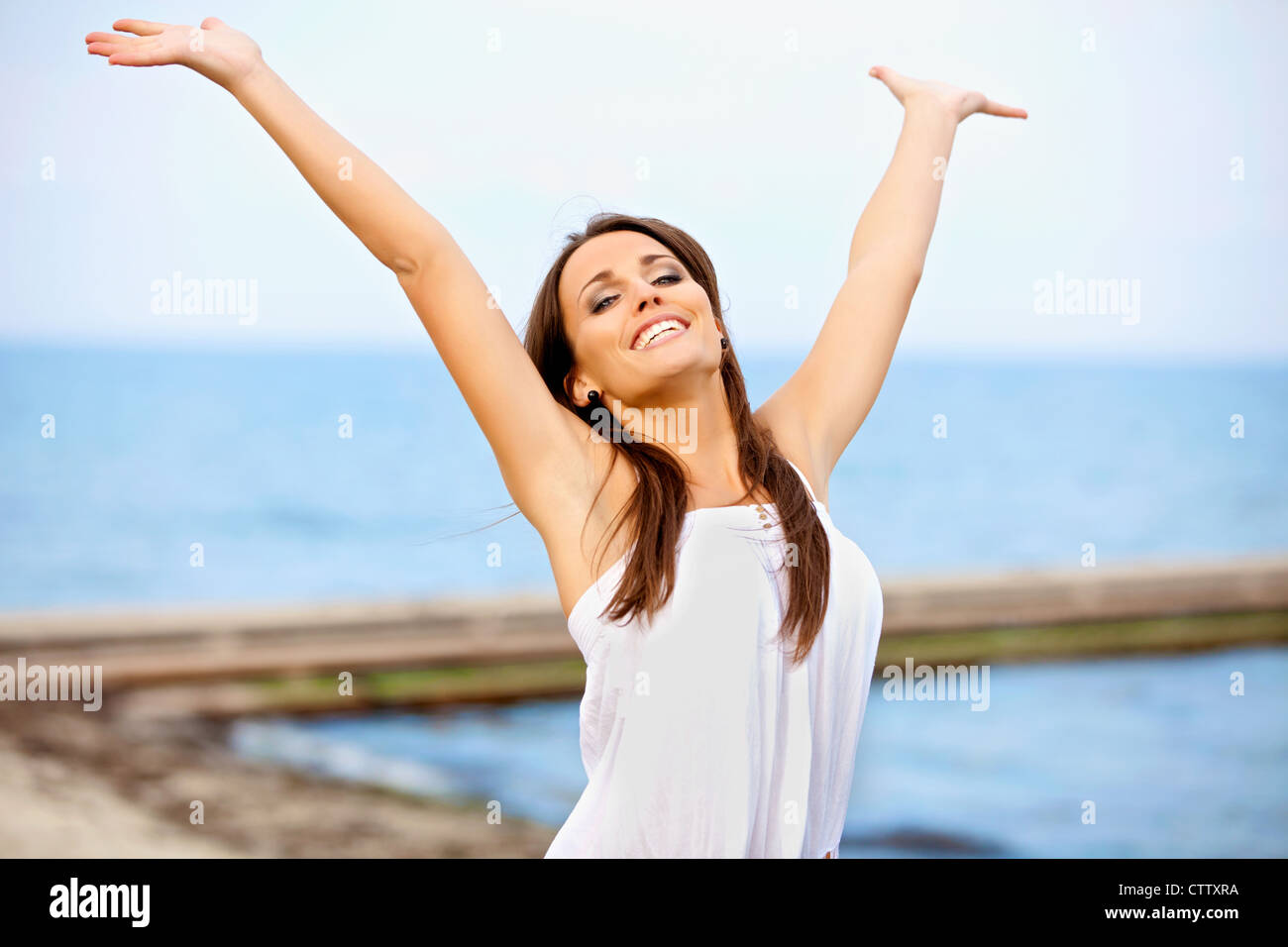 Cheerful woman with arms raised above her head Stock Photo - Alamy