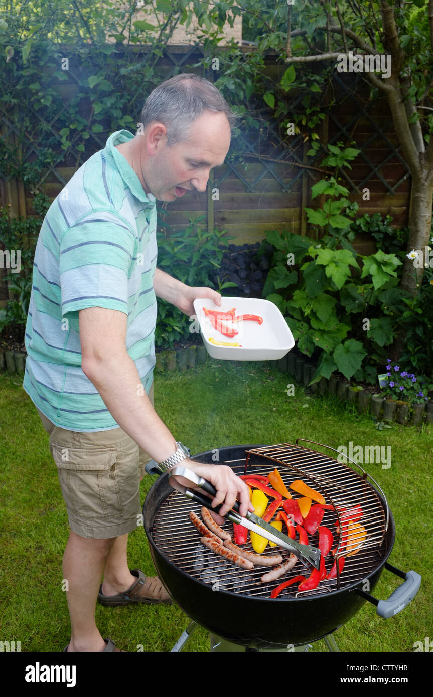 Man cooking on a barbecue in a garden in uk hi-res stock photography ...