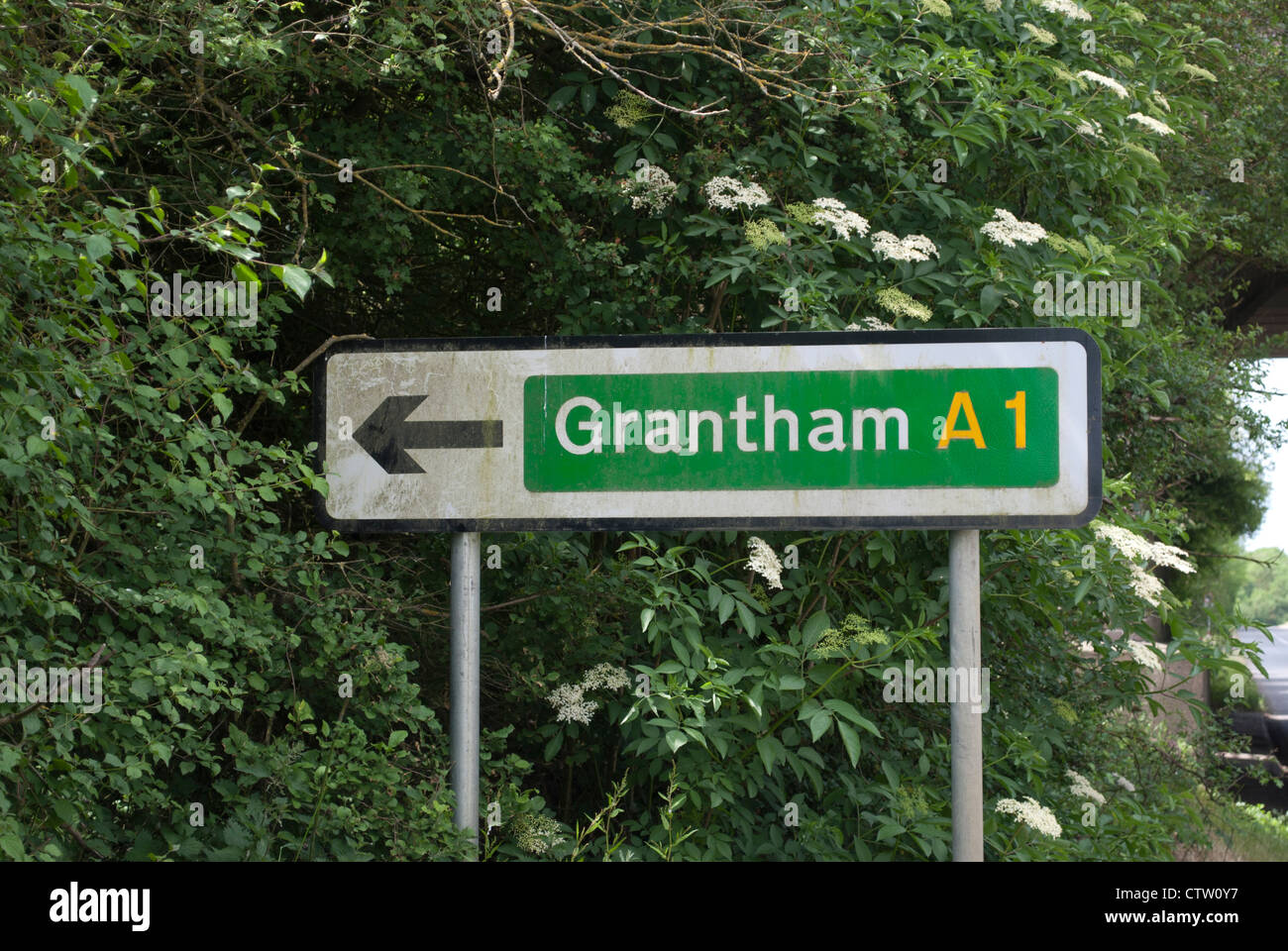 Roadside sign indicating a turn onto the A1 for Grantham with bushes ...