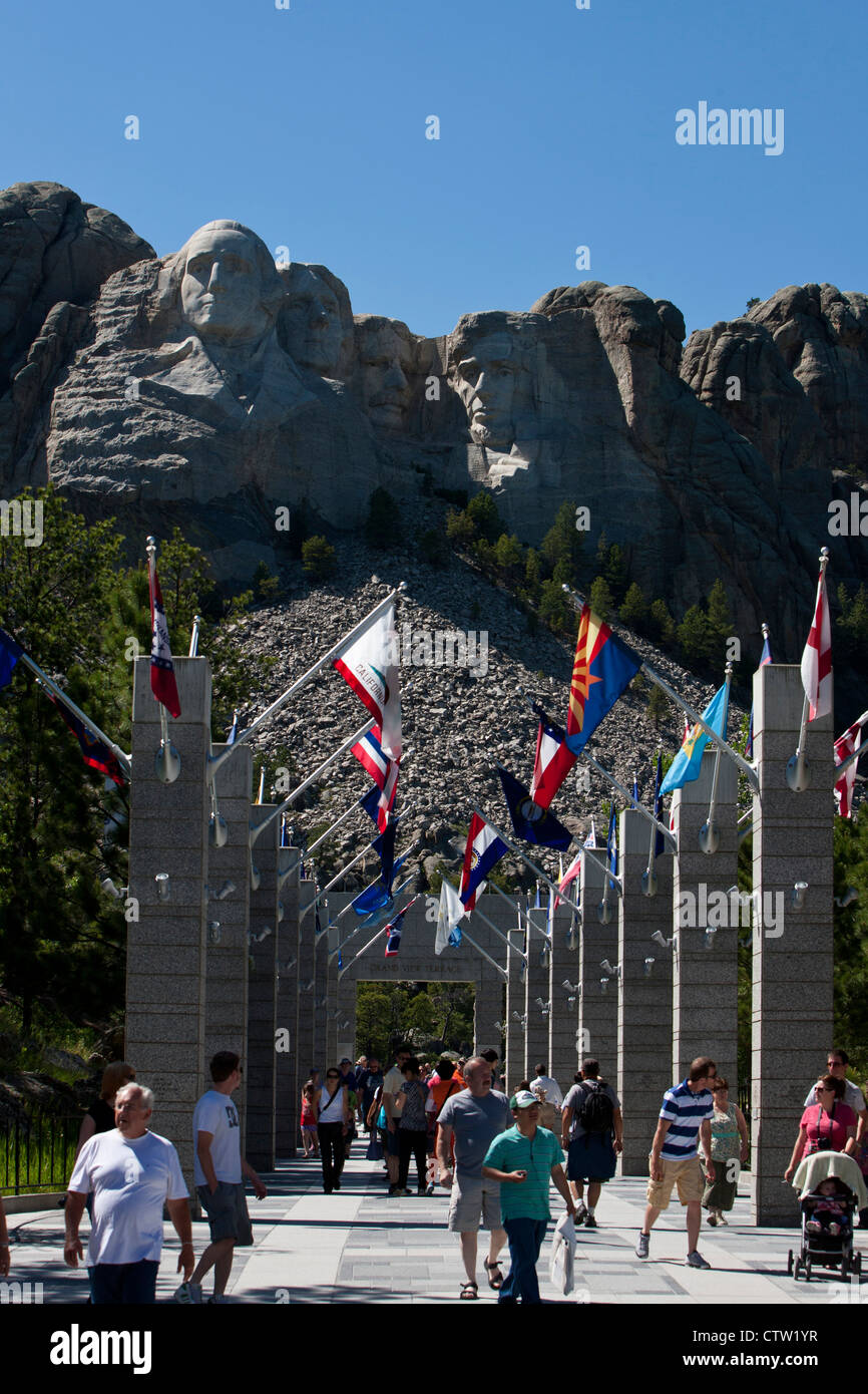 View of Mt. Rushmore with visitors walking along flags of the United ...