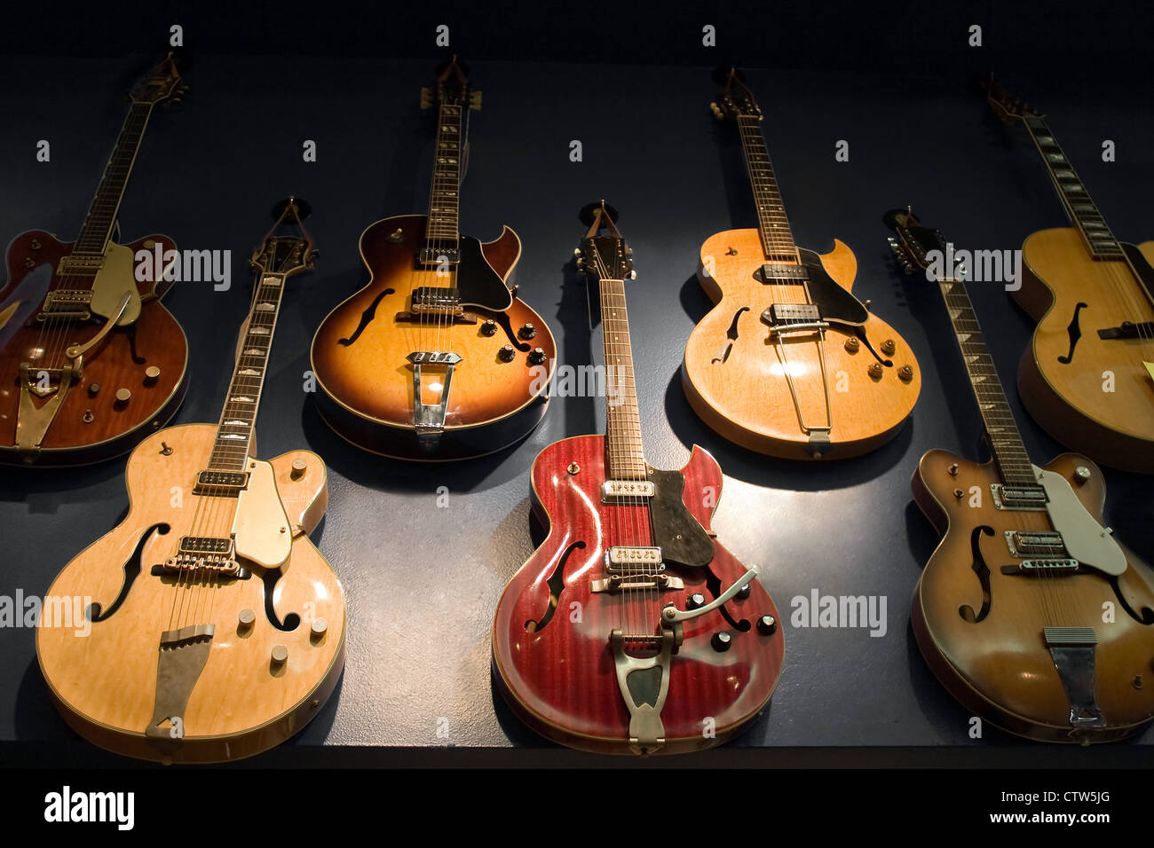 A wall with vintage guitars hanging on display Stock Photo - Alamy