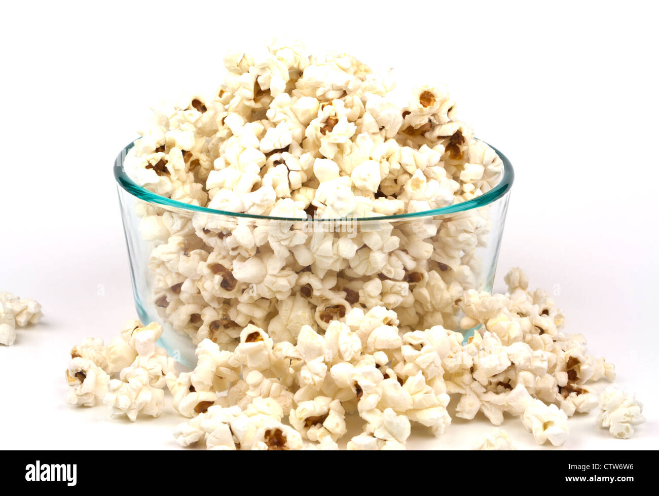 Heap of popcorn overflowing from a clear glass bowl isolated on white ...
