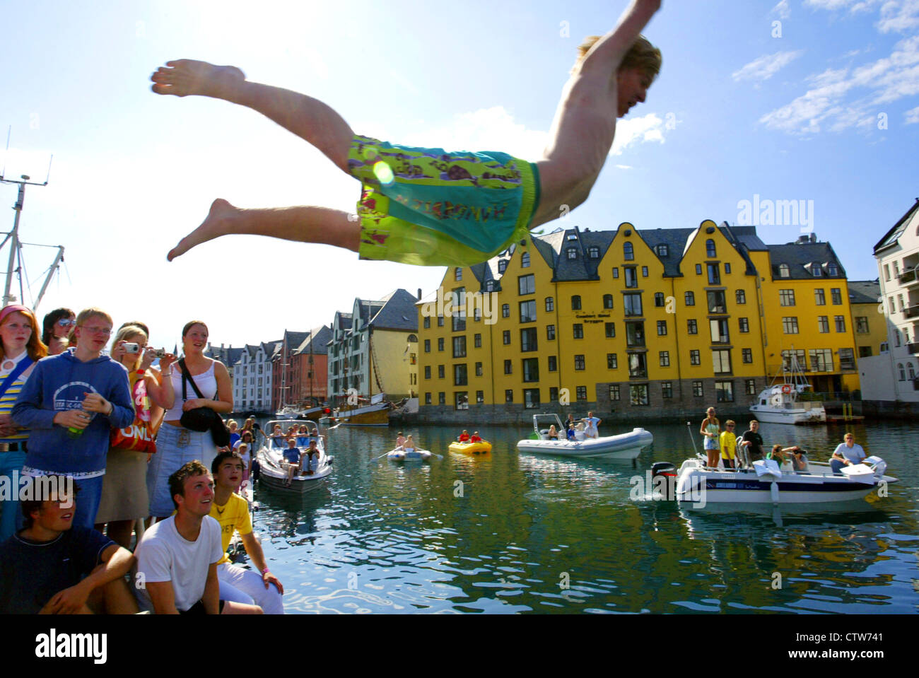Teenager jumping into harbour whilst a crowd watch in Ålesund, Western ...