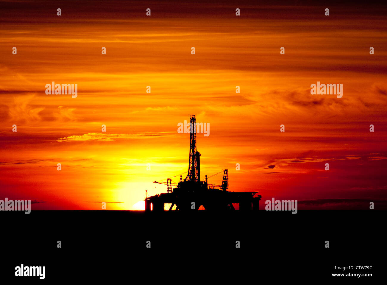 Silhouette of an oil drilling rig in offshore area, during sunset ...