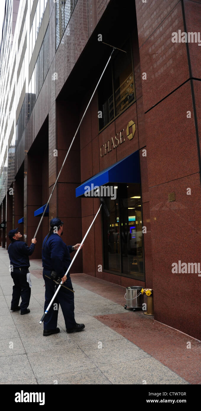 Two men, with telescopic squeegees, cleaning brown marble blue canopy ...