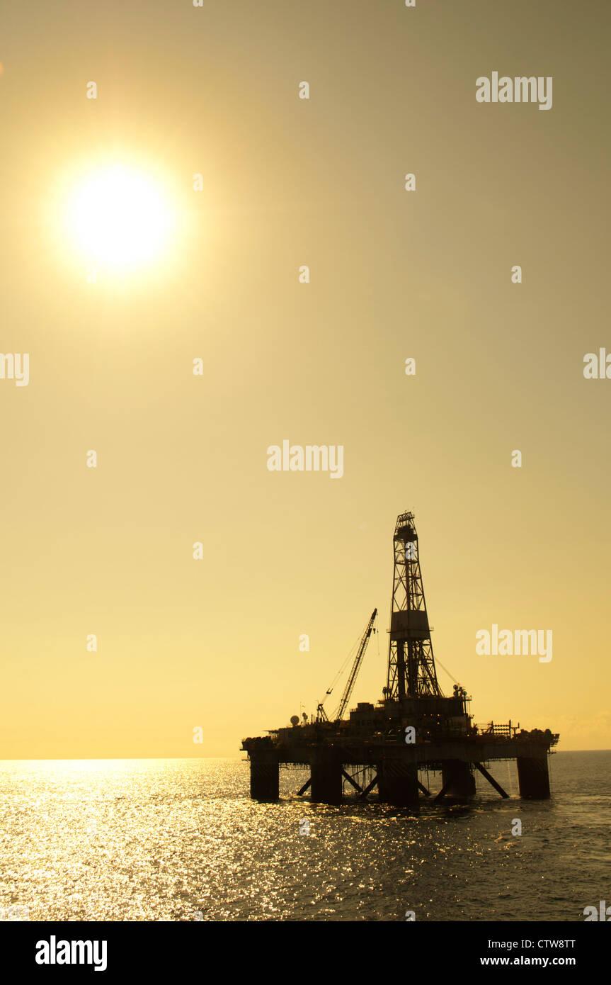 Silhouette of an oil drilling rig in offshore area, during sunset ...