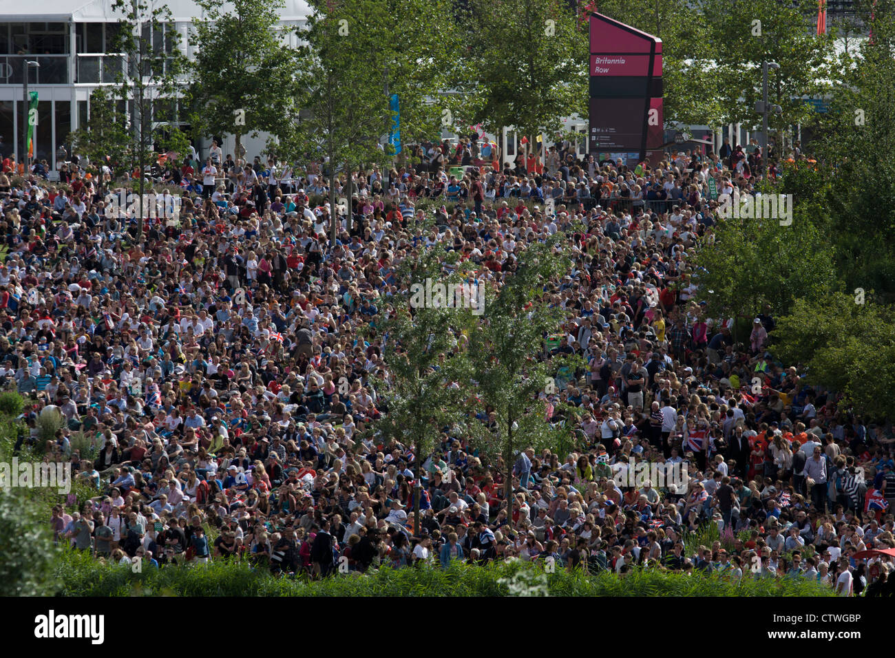 Crowds of spectators gather on grass in the Olympic Park to watch large ...