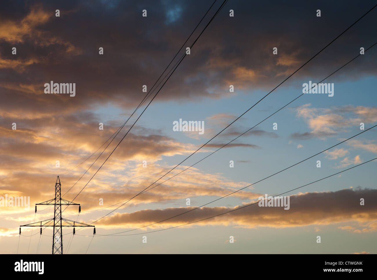 electricity pylon against a nice yellow orange sunset Stock Photo - Alamy