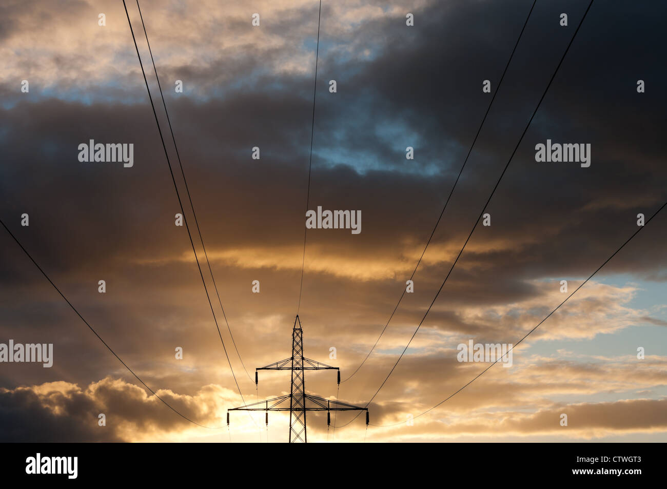 electricity pylons against a nice yellow orange sunset Stock Photo - Alamy